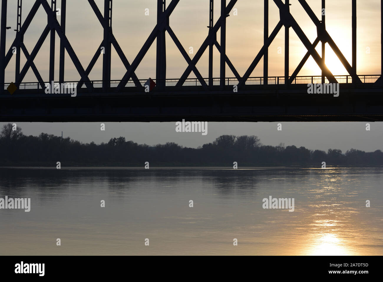 Truss bridge against sunset reflecting on the river below Stock Photo ...