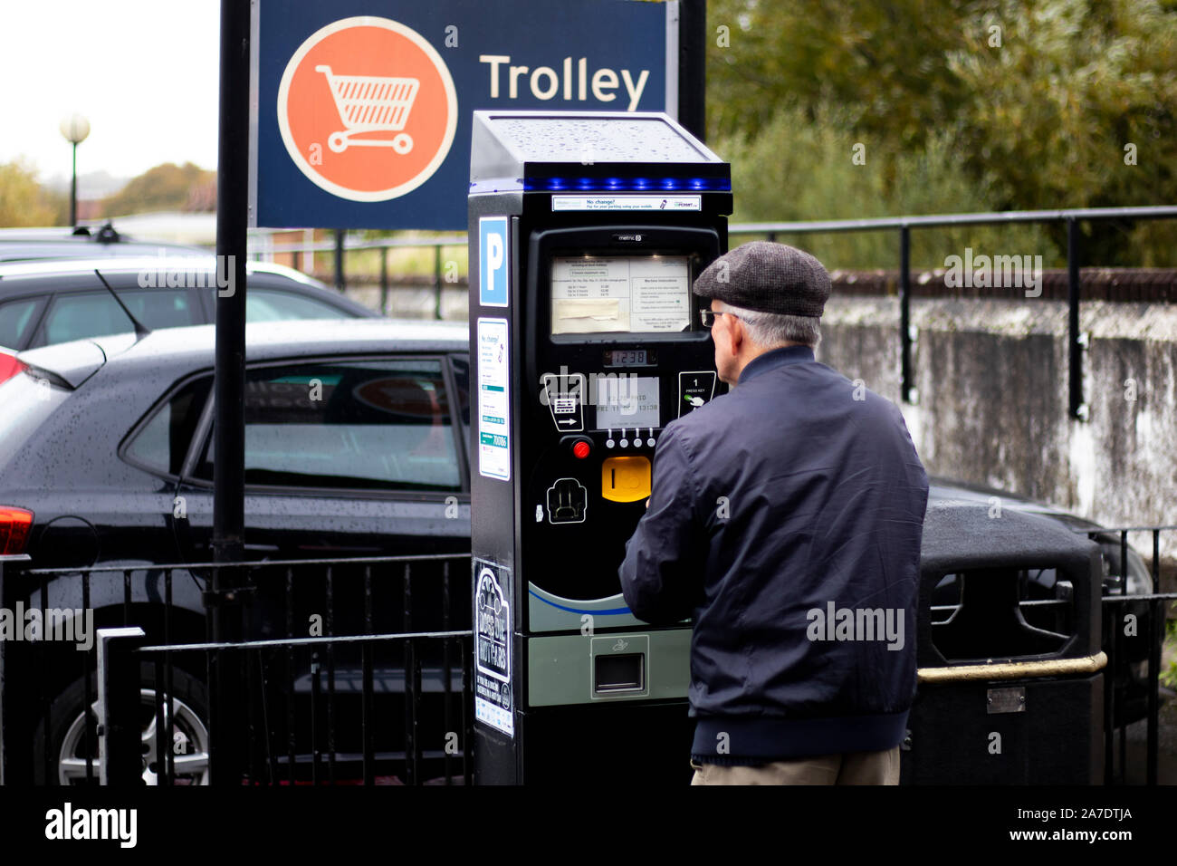 man purchasing parking ticket at city centre car park ticket machine ...