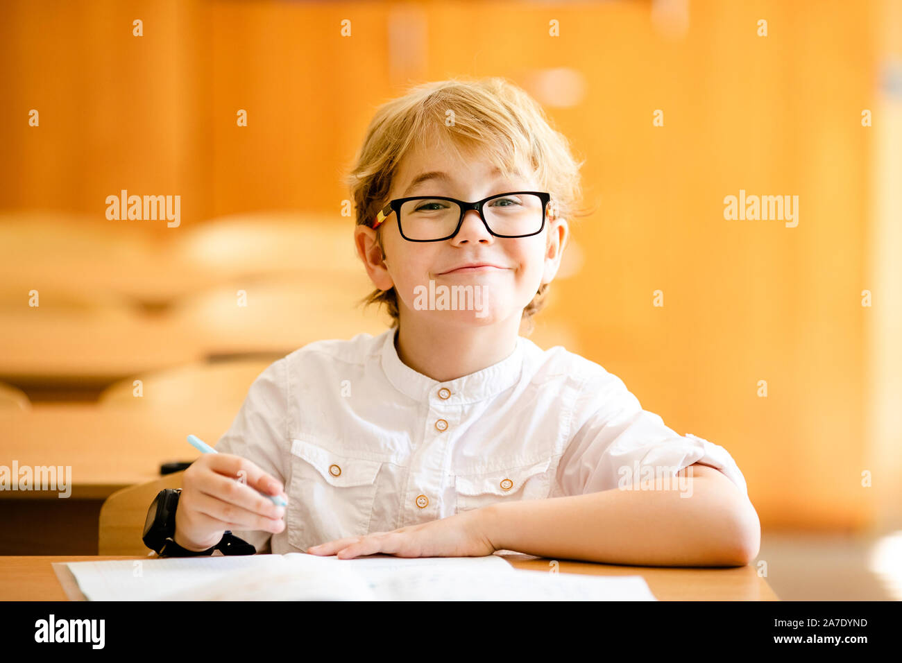 Seven years old child with glasses writing his homework at school. Boy ...