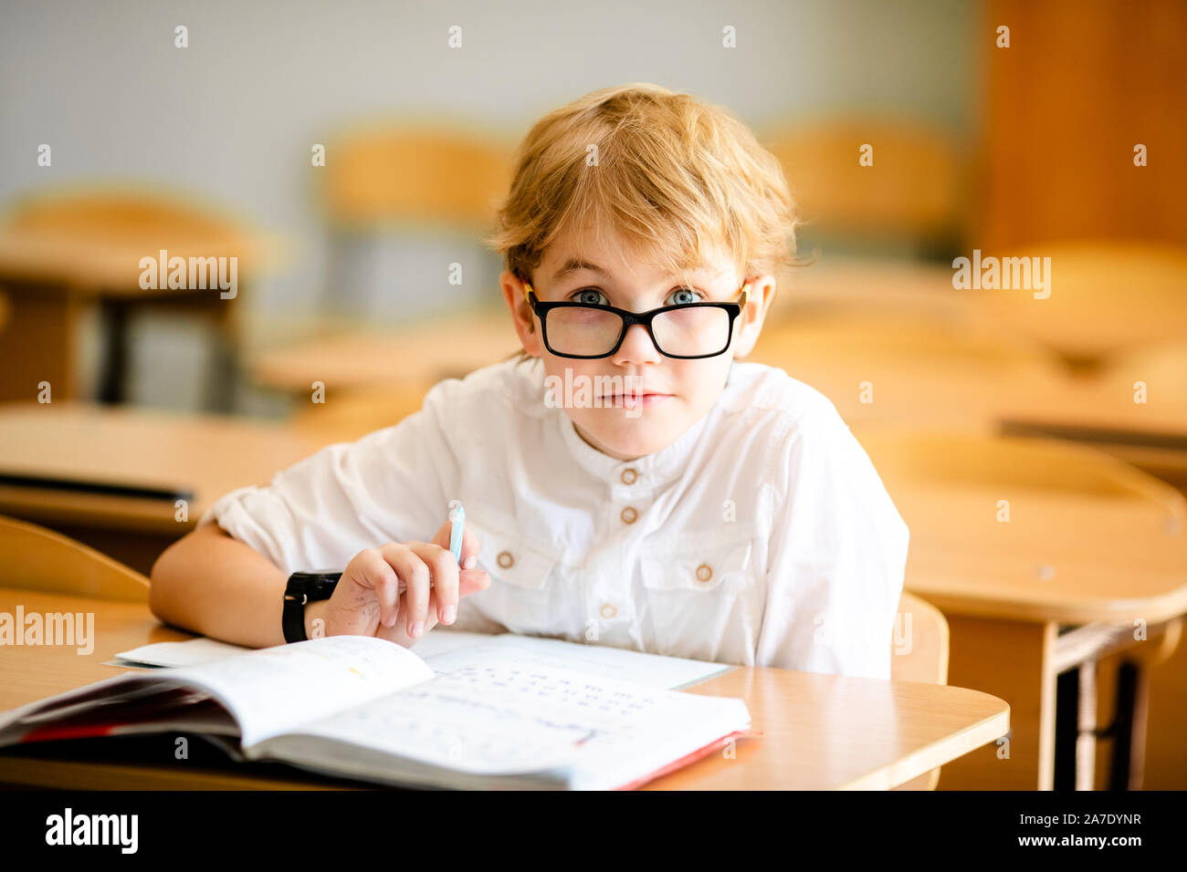 Seven years old child with glasses writing his homework at school. Boy ...