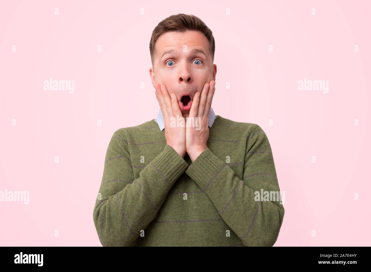 Young man with a shocked facial expression on pink background Stock ...