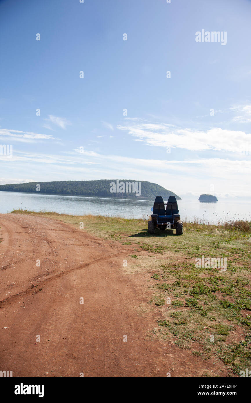 off road terrian vehicle sits by an empty dirt path on the shoreline ...