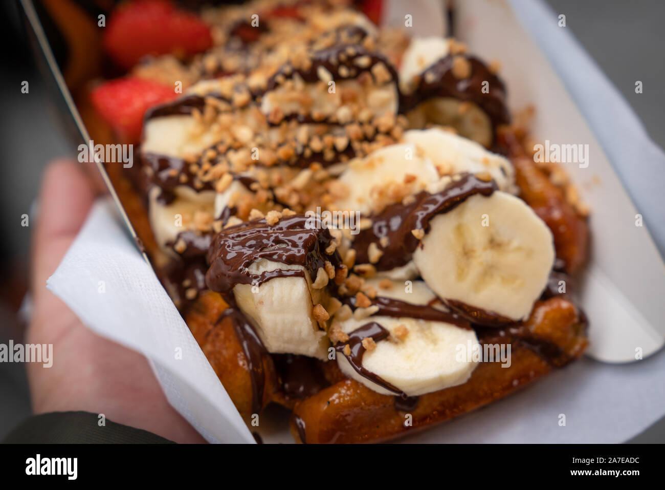 Hand holding homemade Belgian waffles with honey, banana, strawberry ...