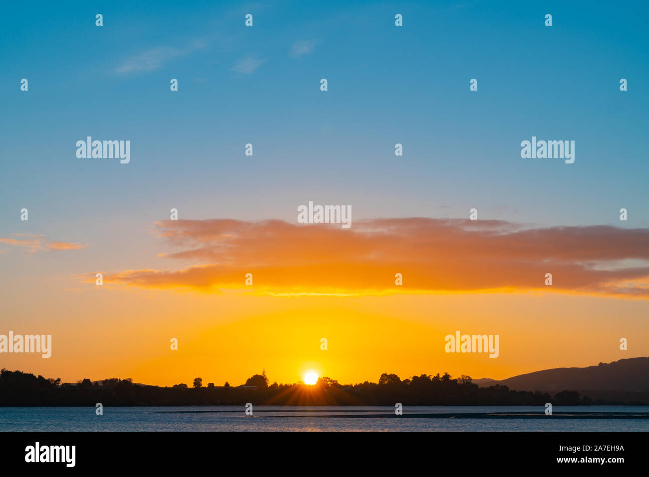 Clear summer sunrise over low silhouette horizon with cloud catching ...