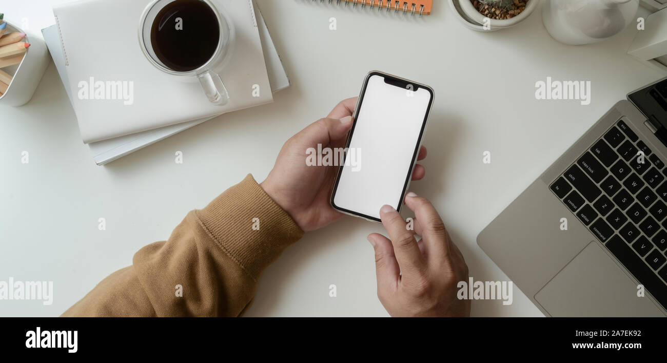 Top view of young male freelancer holding blank screen smartphone in his modern workplace Stock ...