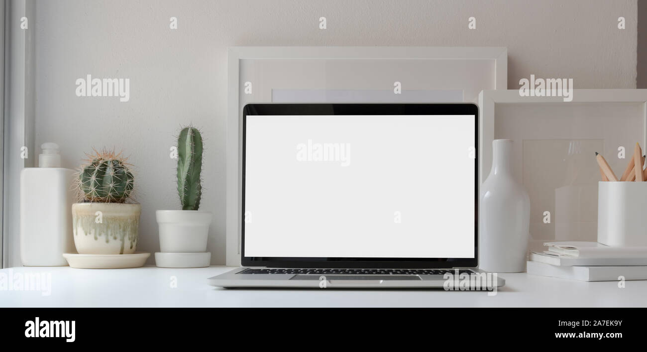 Open blank screen laptop computer in minimal workspace with cactus pots ...