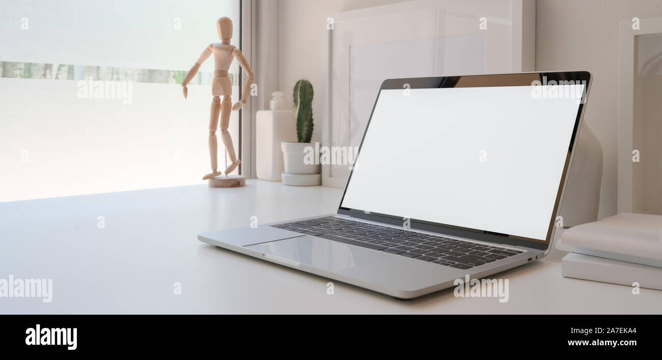 Open blank screen laptop computer in minimal workspace with cactus pots ...