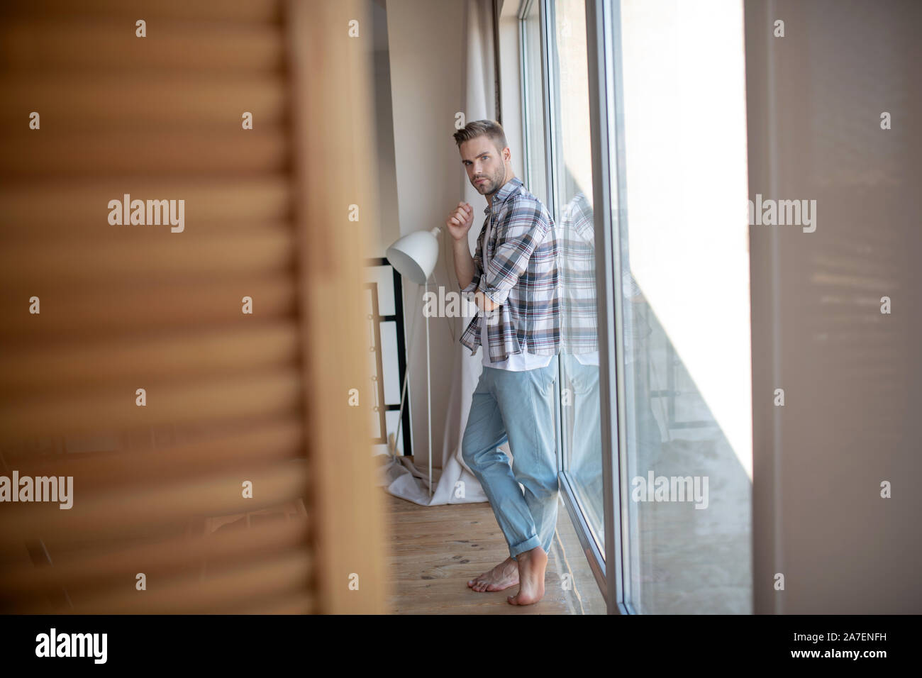 Handsome young man standing near window at the weekend Stock Photo - Alamy