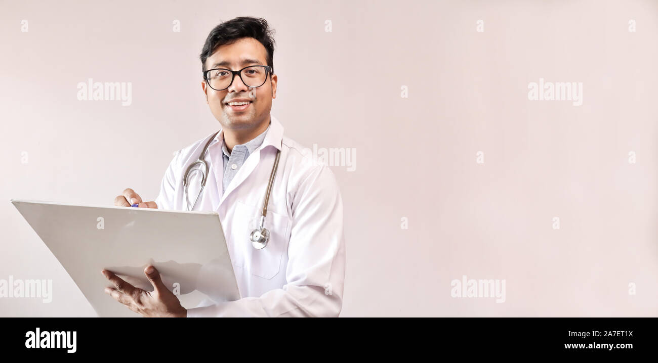 male indian doctor in white coat and stethoscope writing notes and ...