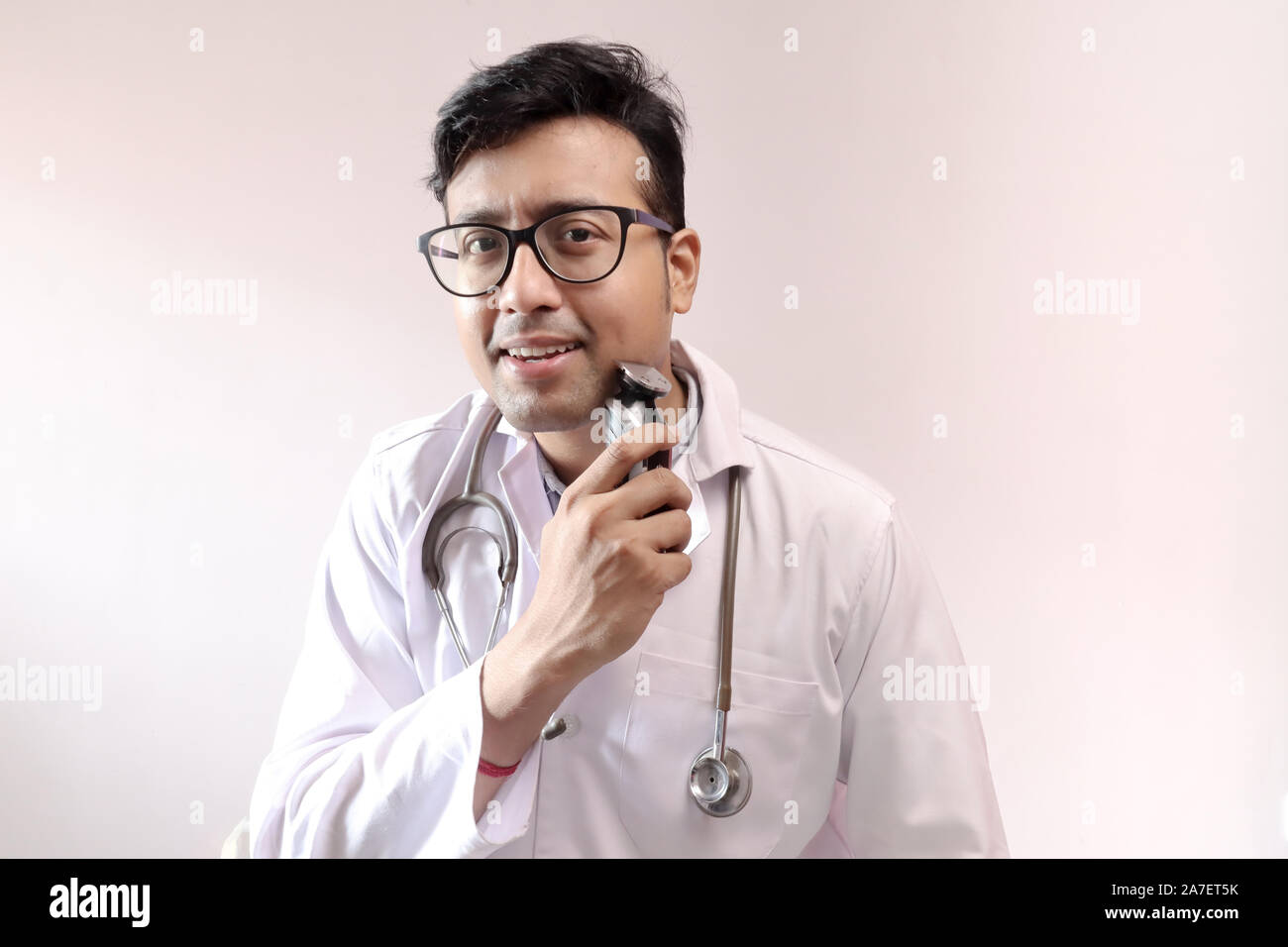 male indian doctor in white coat and stethoscope trimming beard with ...