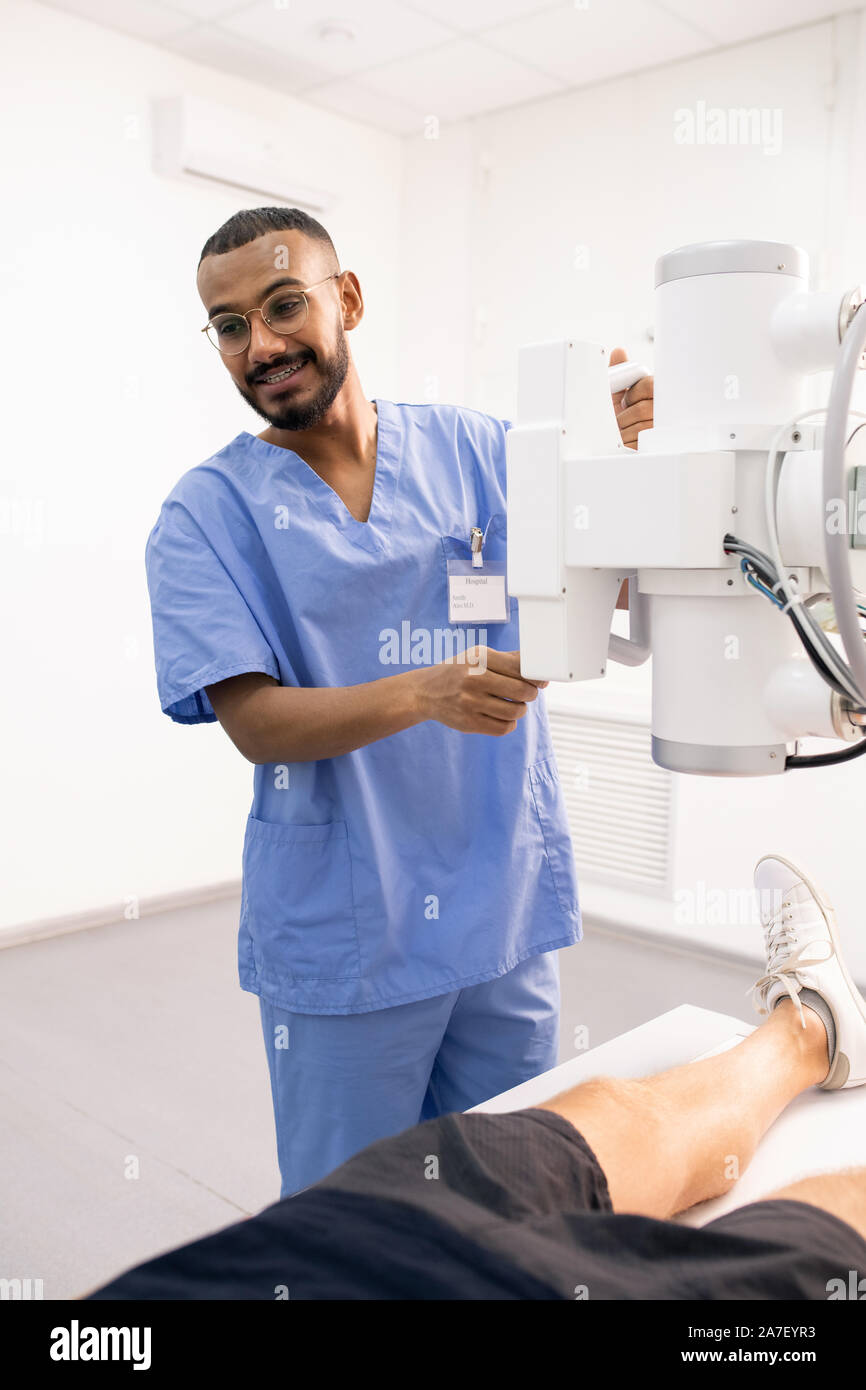 Young smiling doctor in blue uniform using new medical equipment Stock ...