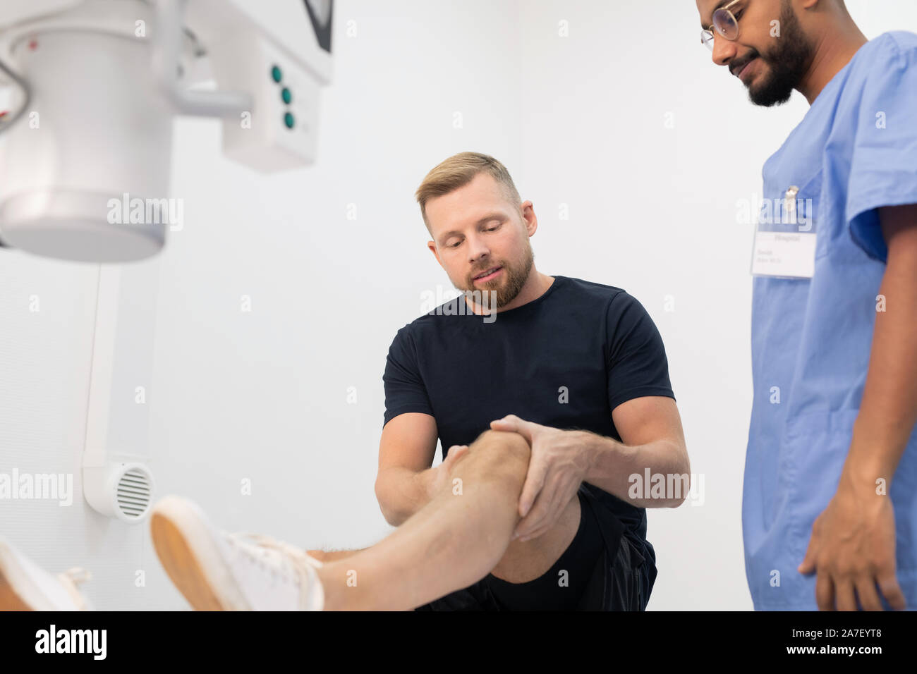 Young man showing sick leg or knee while describing his problem to ...