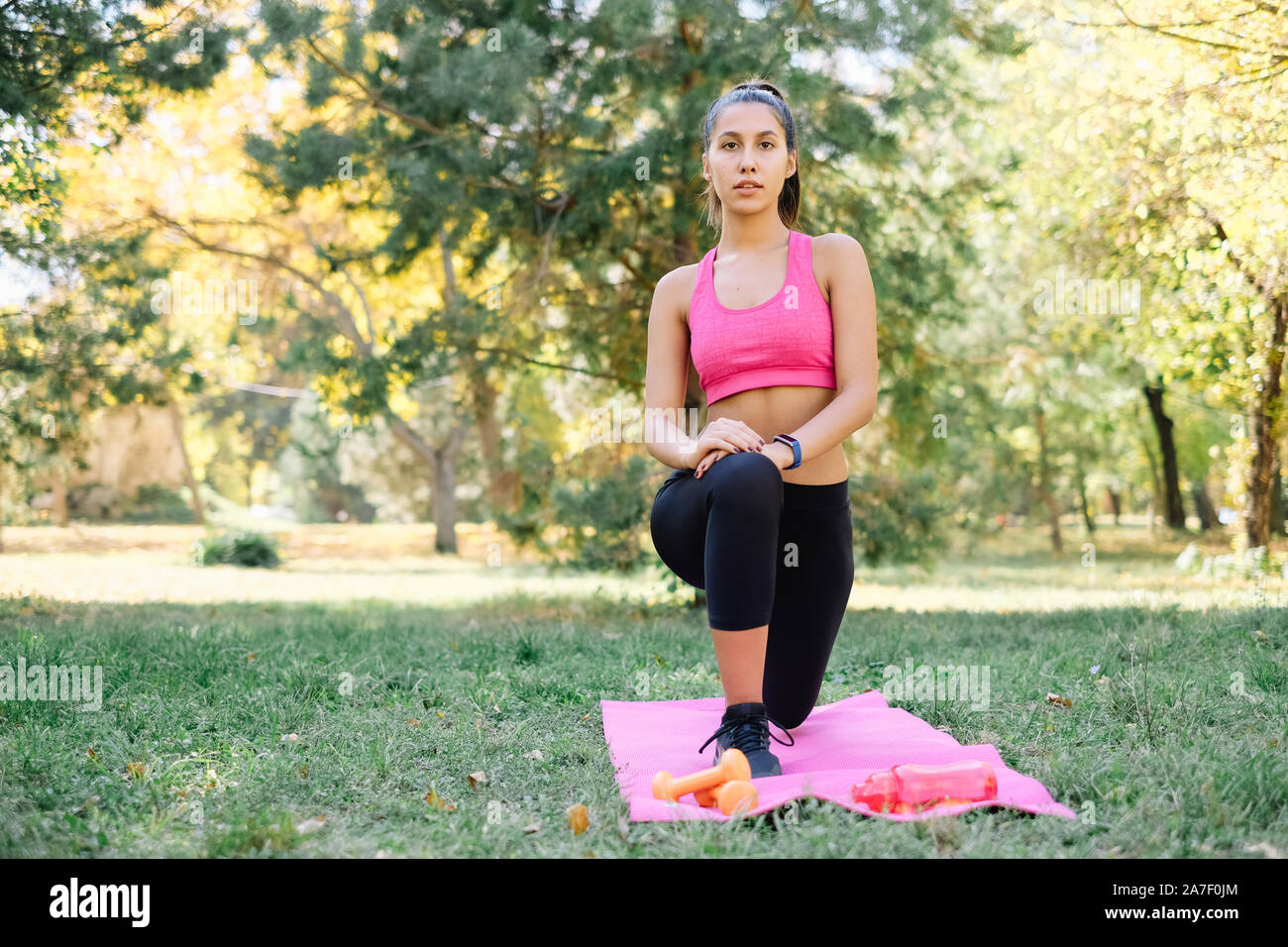 Brunette woman doing forward lunges on pink mat Stock Photo - Alamy