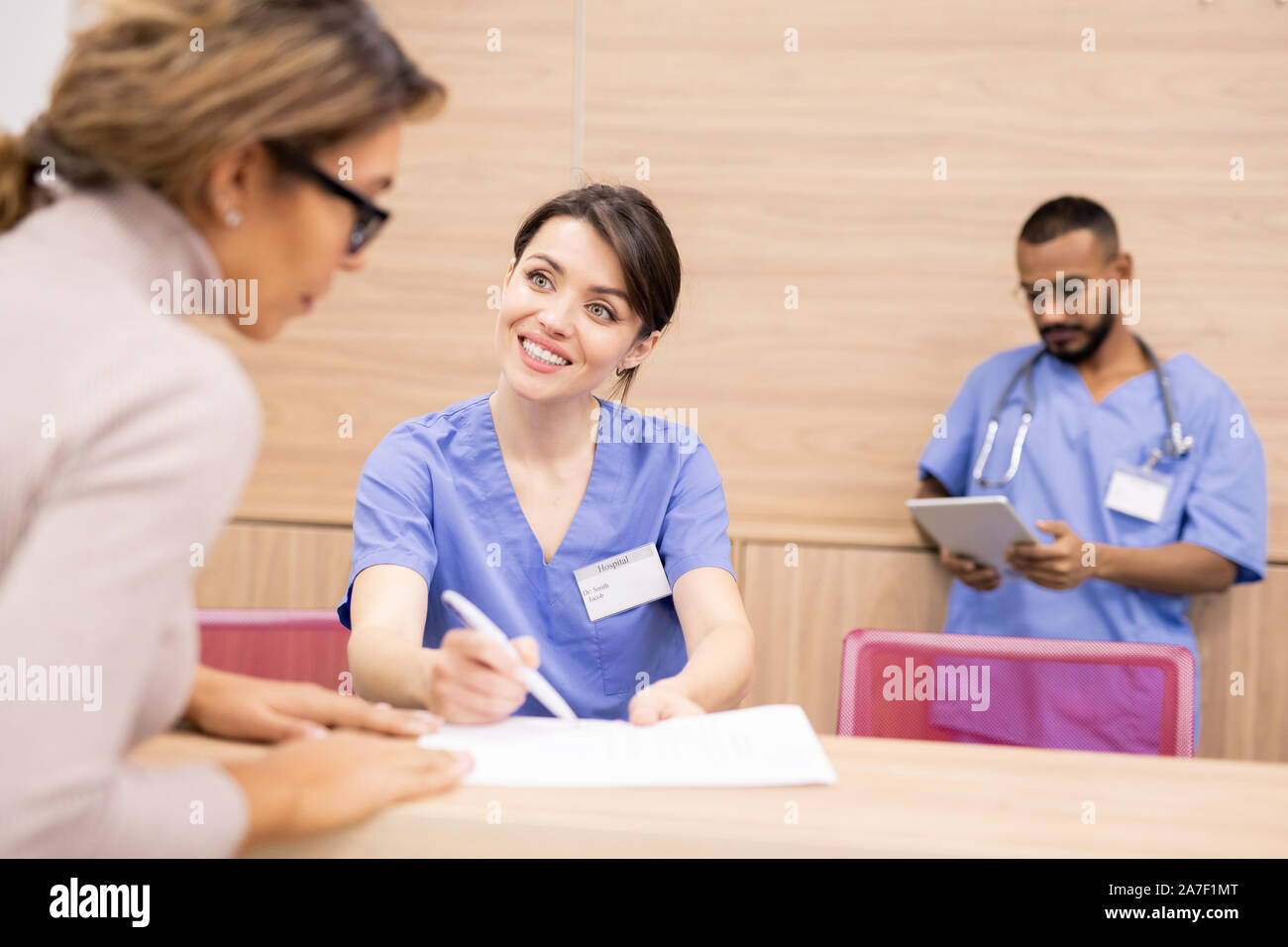 Clinician in uniform smiling at patient while pointing at medical ...