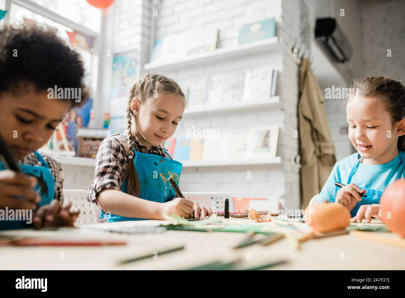 Two cute diligent girls and African boy drawing with highlighters by ...
