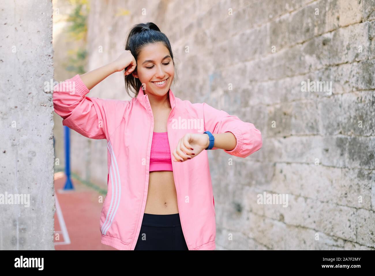 Young woman with watch resting against wall Stock Photo - Alamy