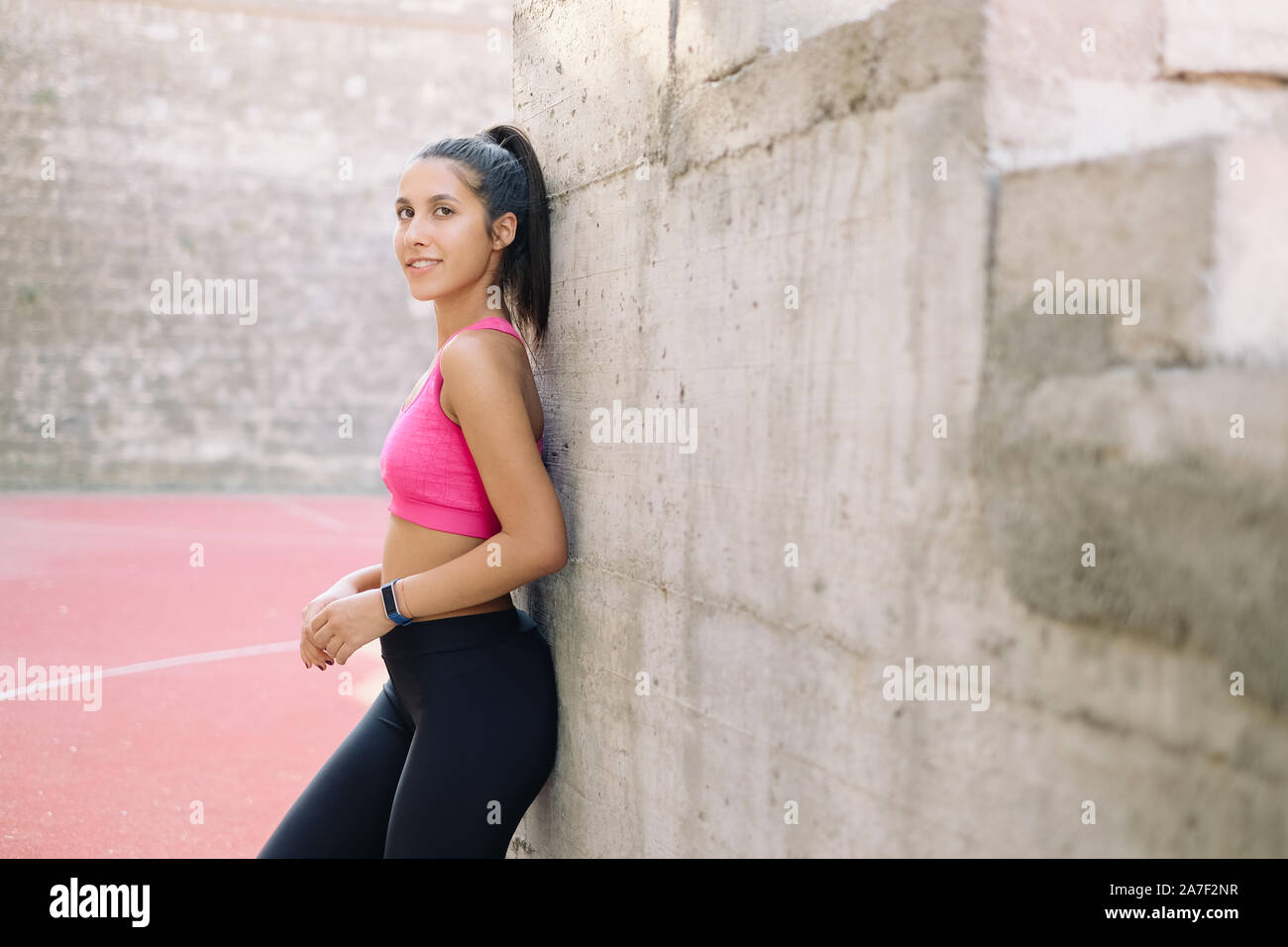 Smiling girl standing and resting against wall Stock Photo - Alamy