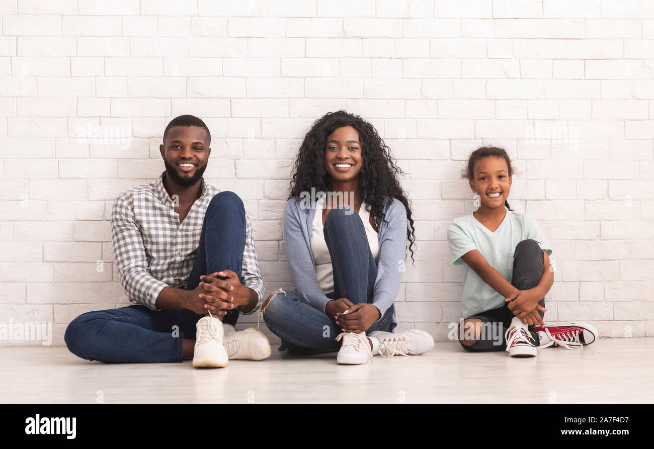 Cute millennial family sitting on floor in similar pose Stock Photo - Alamy