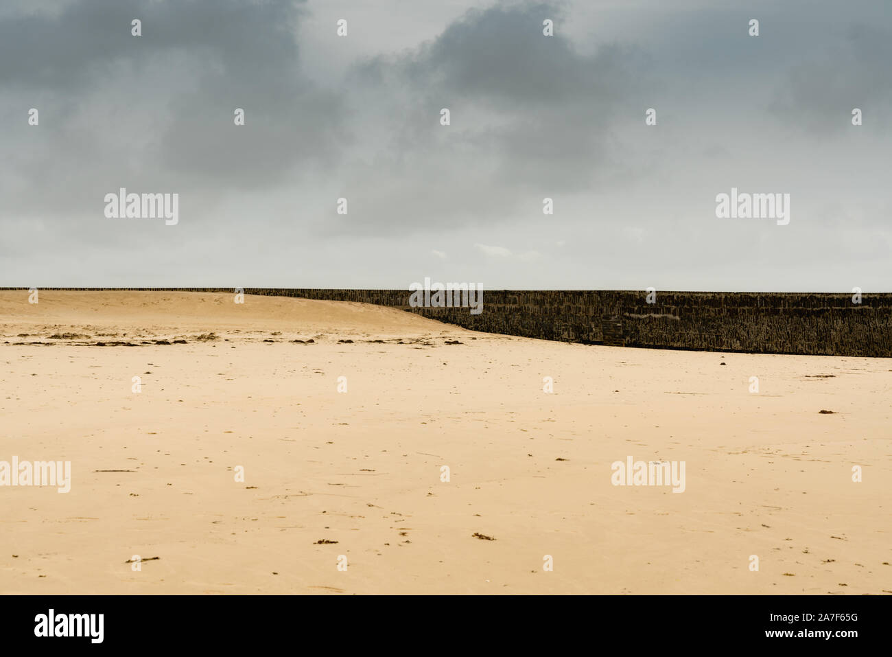 A minimalist abstract landscape of stone harbor wall and beach under an ...