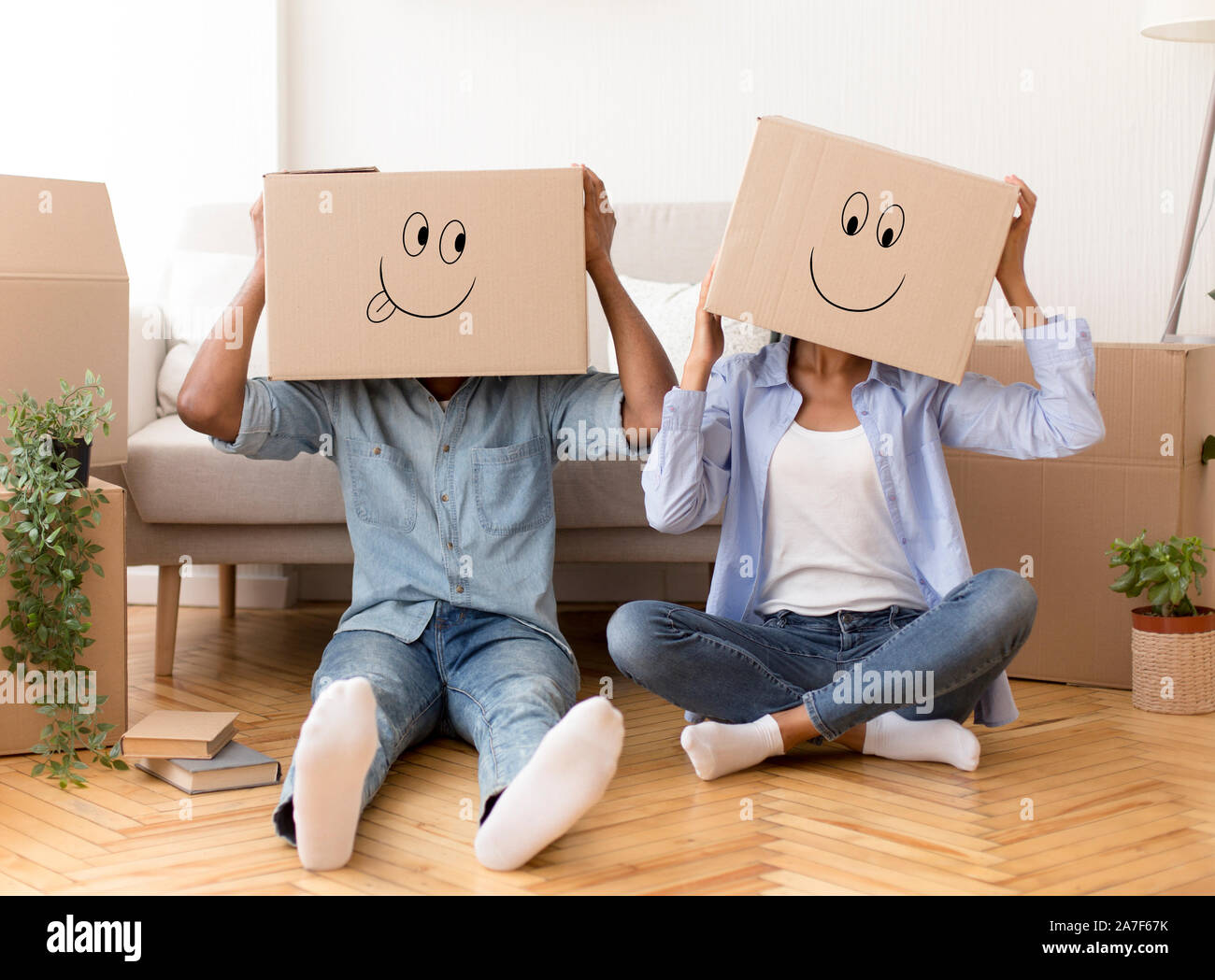 Couple Wearing Moving Boxes On Head Sitting On Floor Indoor Stock Photo ...