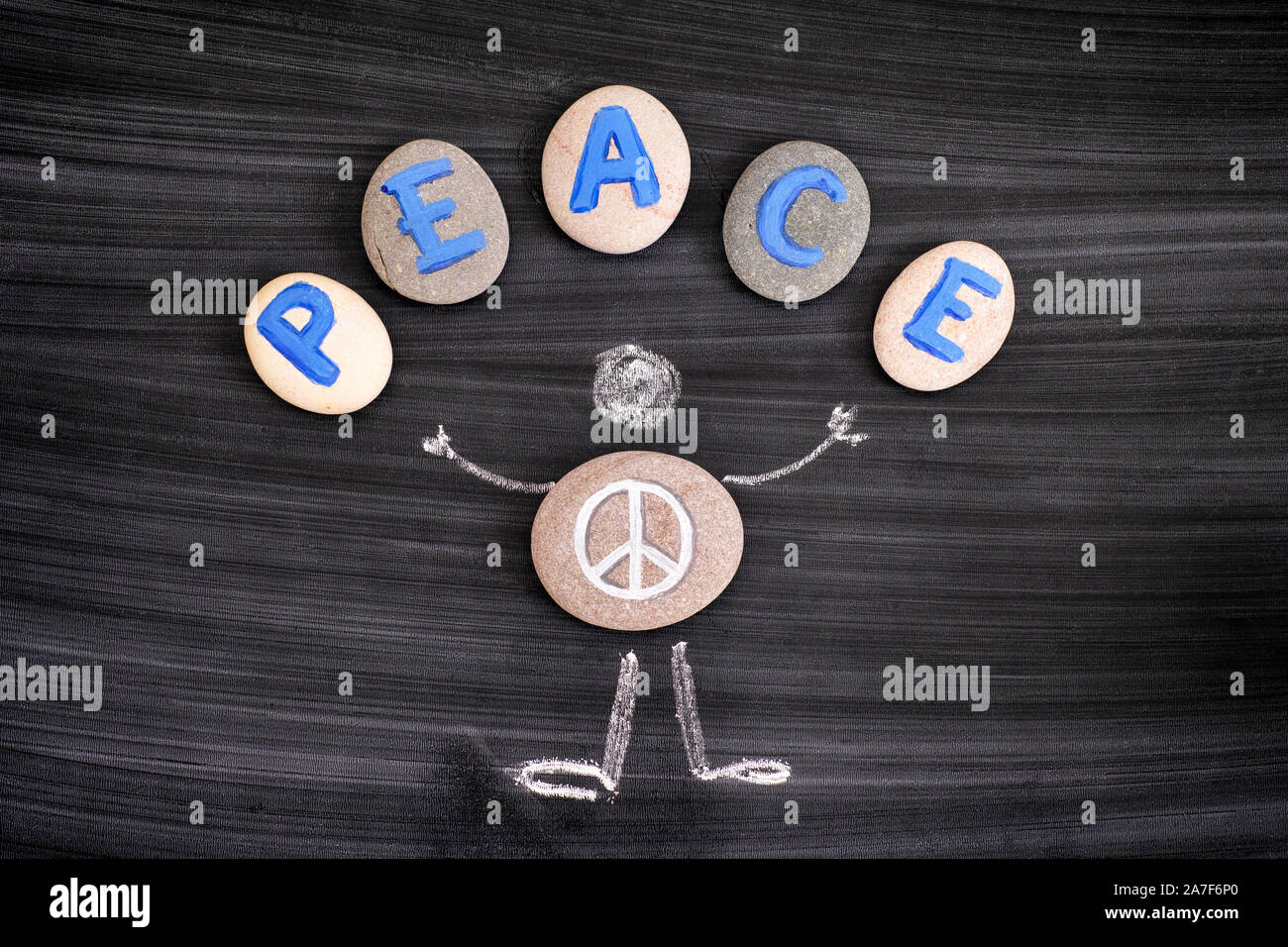 Pebble with peace symbol inside chalk drawing of man and letters PEACE ...