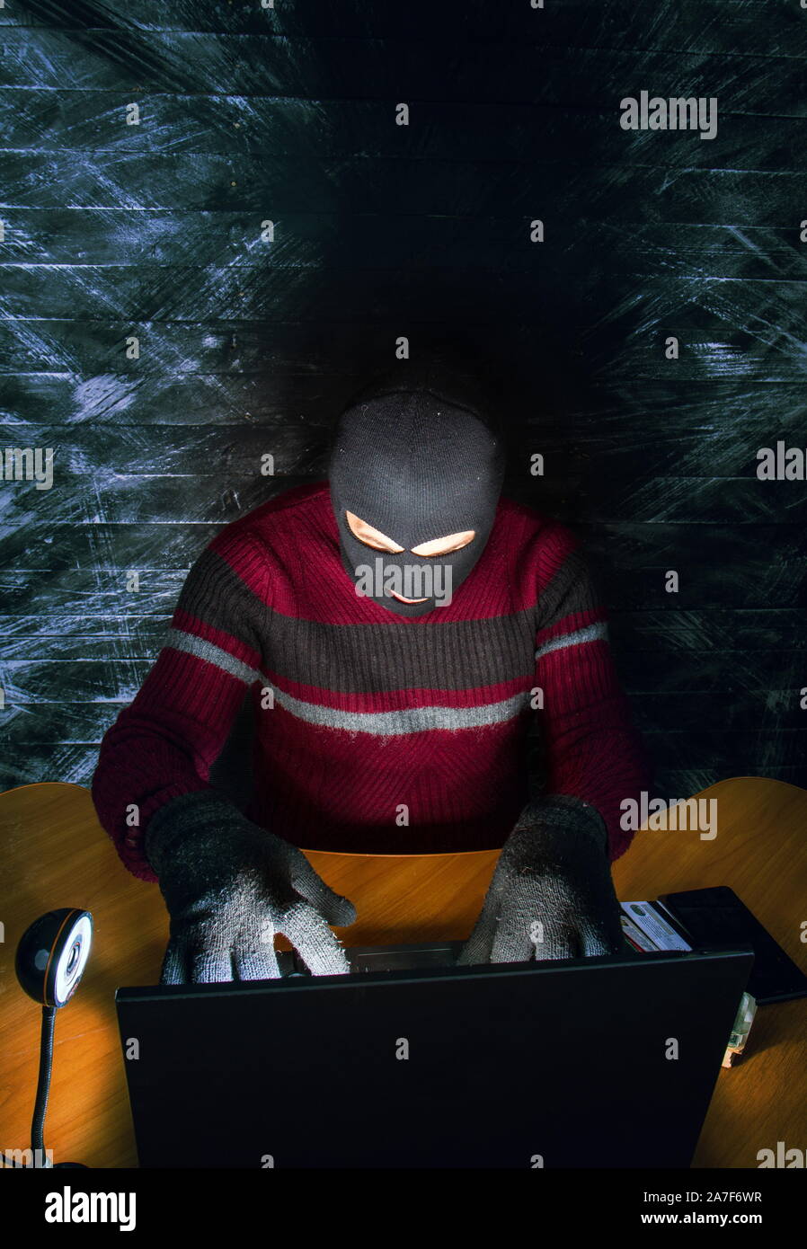 a bandit in a mask of a balaclava using a laptop does not fair profit ...