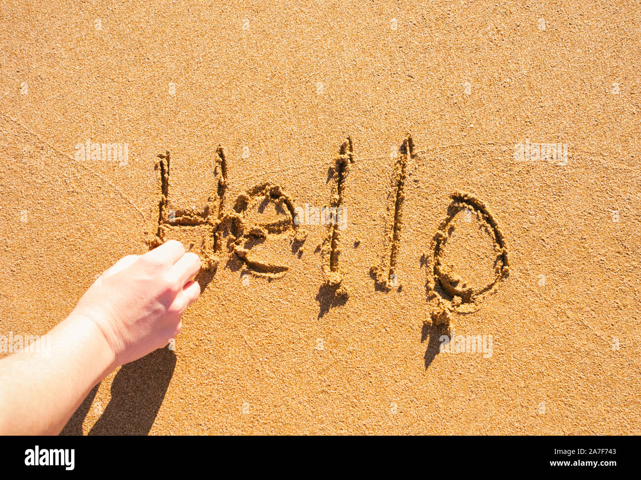 Woman hand written Word Hello on sea sand. Close up Stock Photo - Alamy