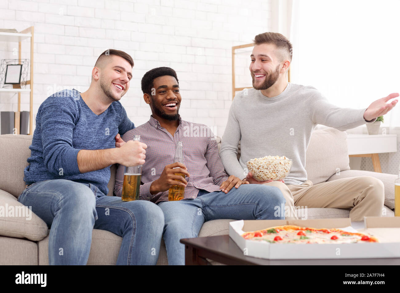 Three football fans watching game on TV at home Stock Photo - Alamy