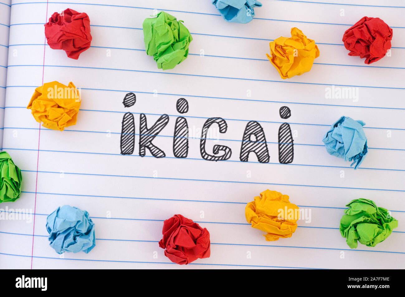 The word Ikigai on notebook sheet with some colorful crumpled paper ...