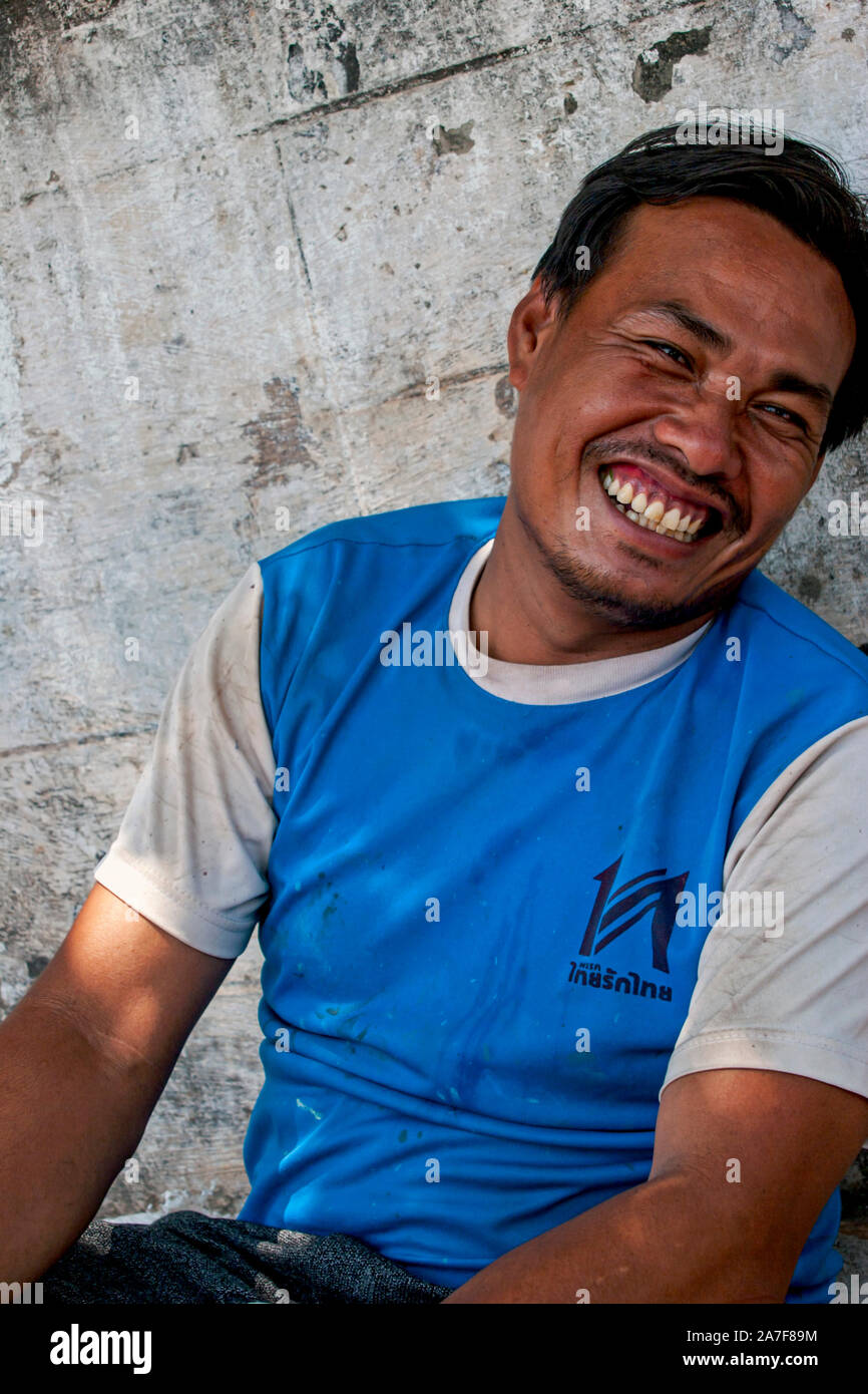 A young and happy relaxed Thai man is enjoying is day on a city street ...