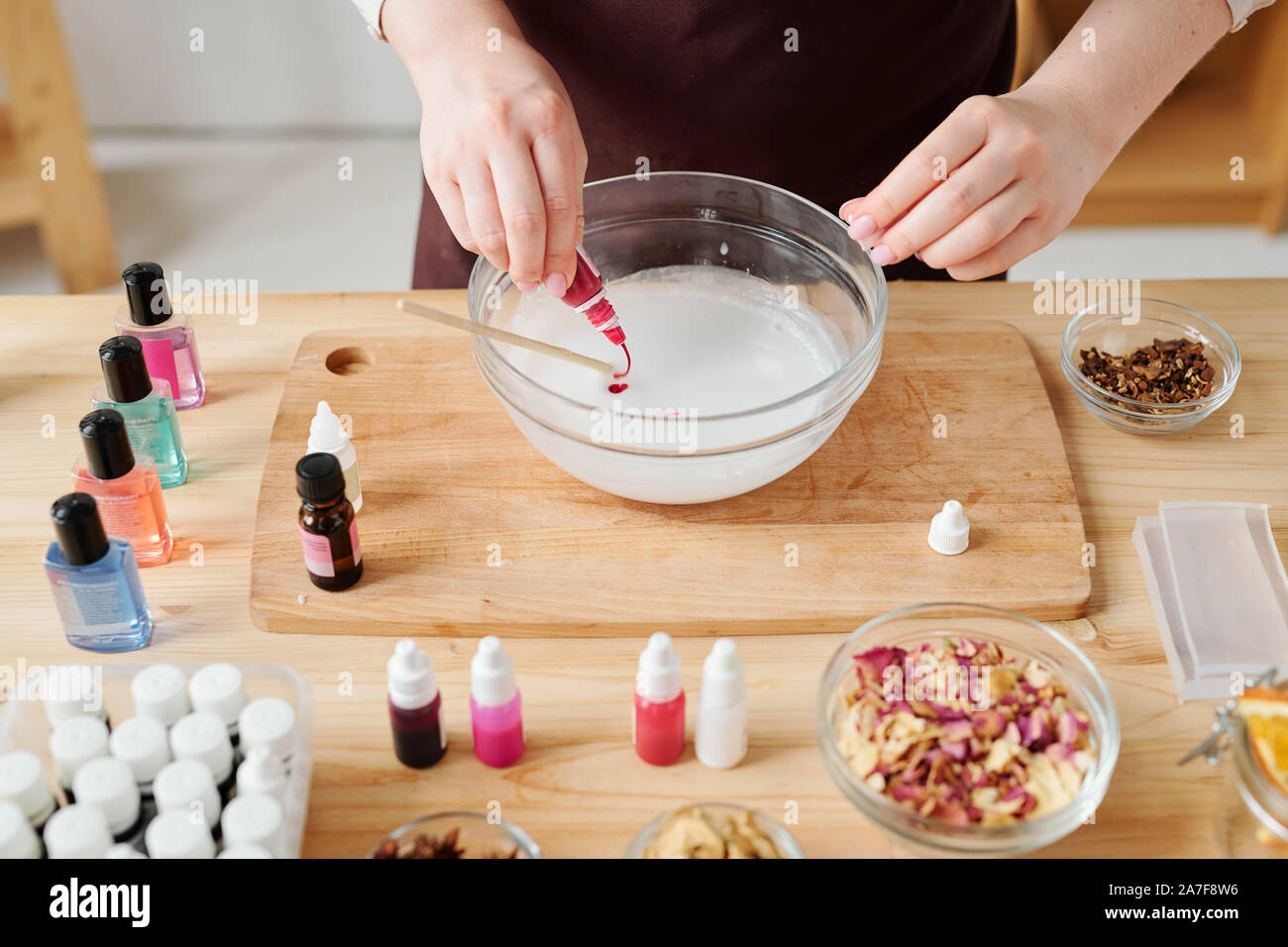 Hands of girl putting color from small plastic bottle into liquid soap ...