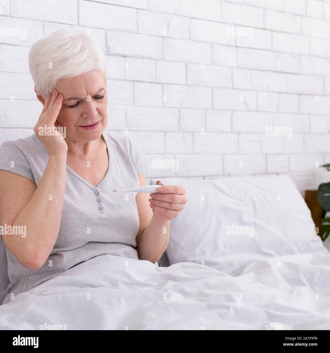 Sick senior lady with fever measuring body temperature in bed Stock ...