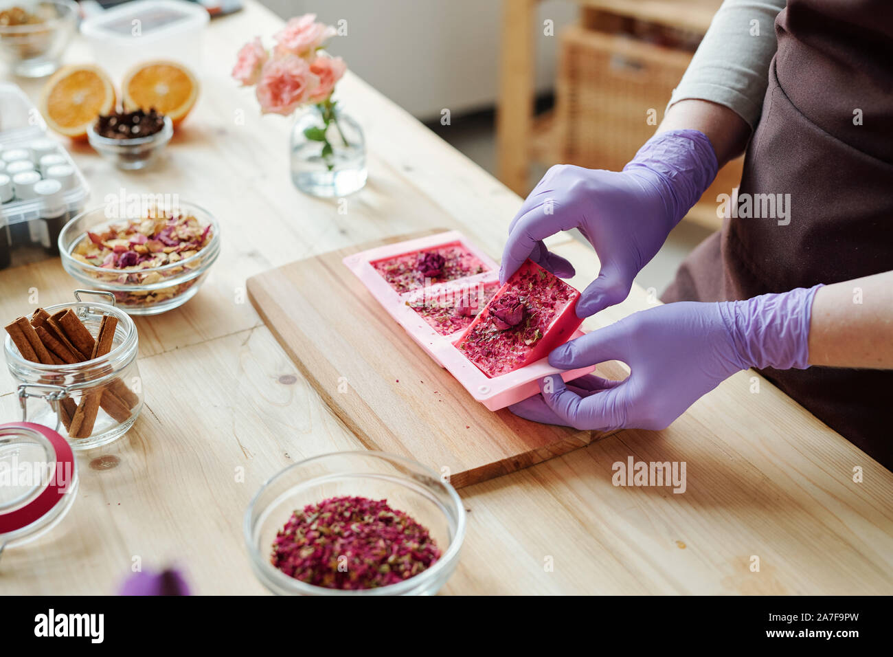 Hands of young woman taking out fresh handmade pink soap from silicone ...