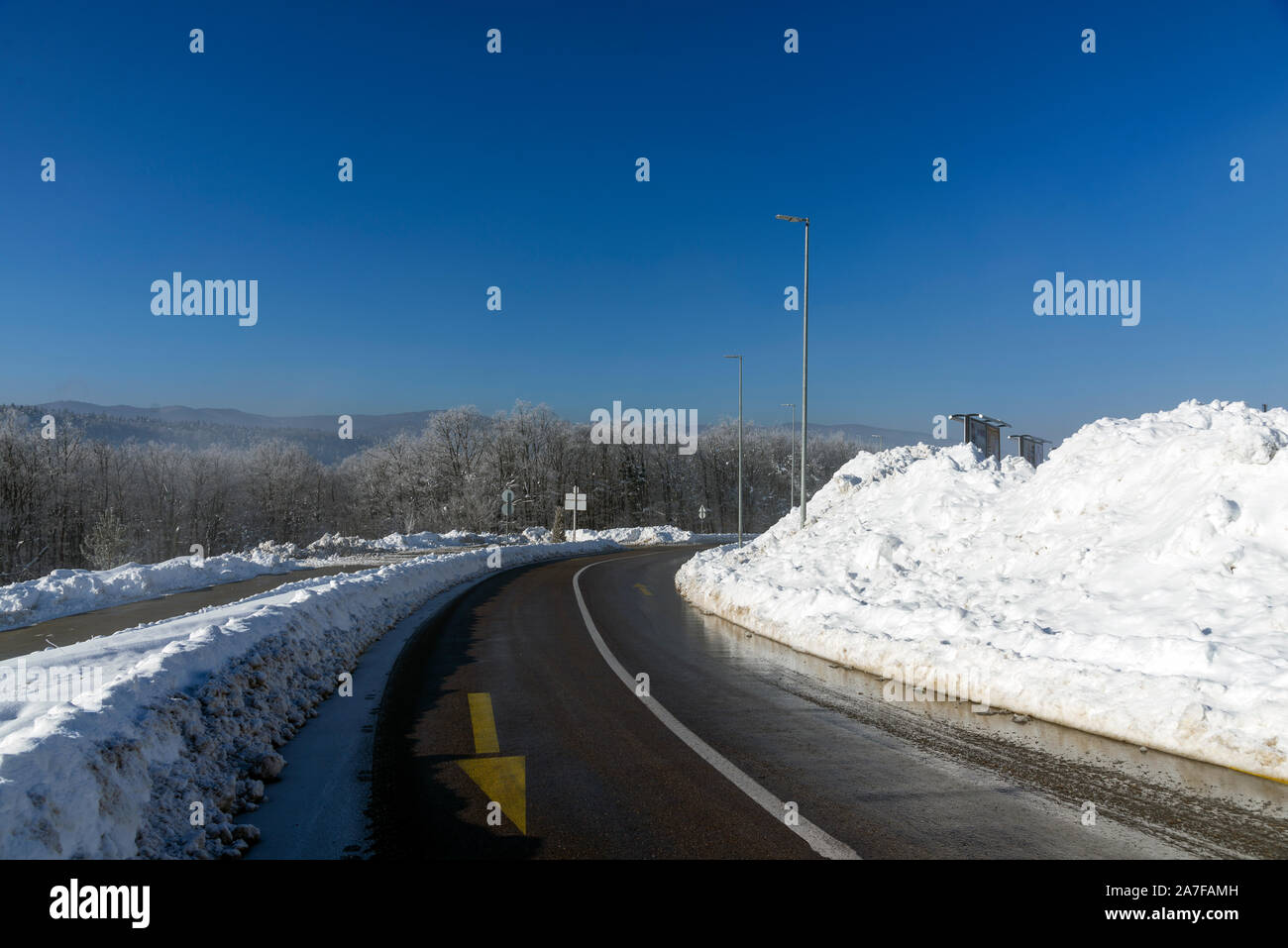 Snowy bending road scene in winter, with snowy trees, rocks and asphalt ...