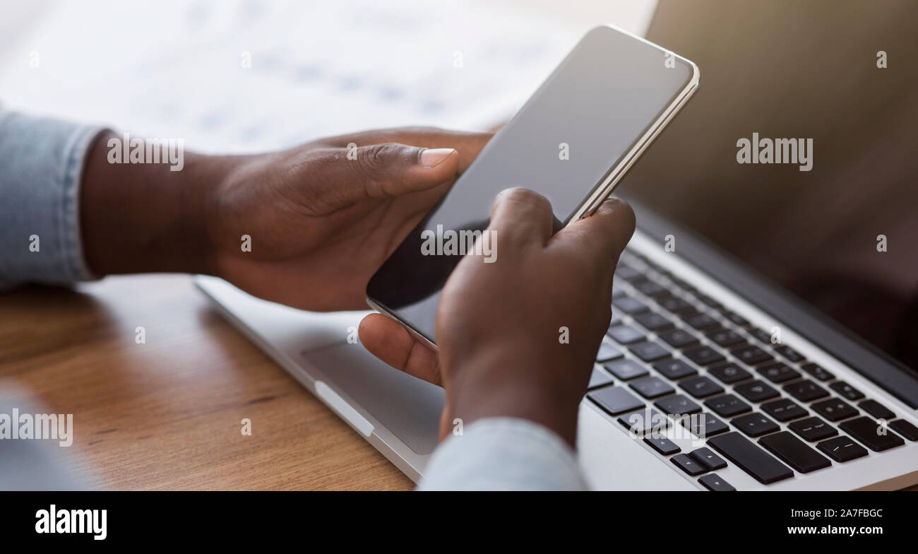 Black male hands using smartphone with blank screen and laptop Stock ...