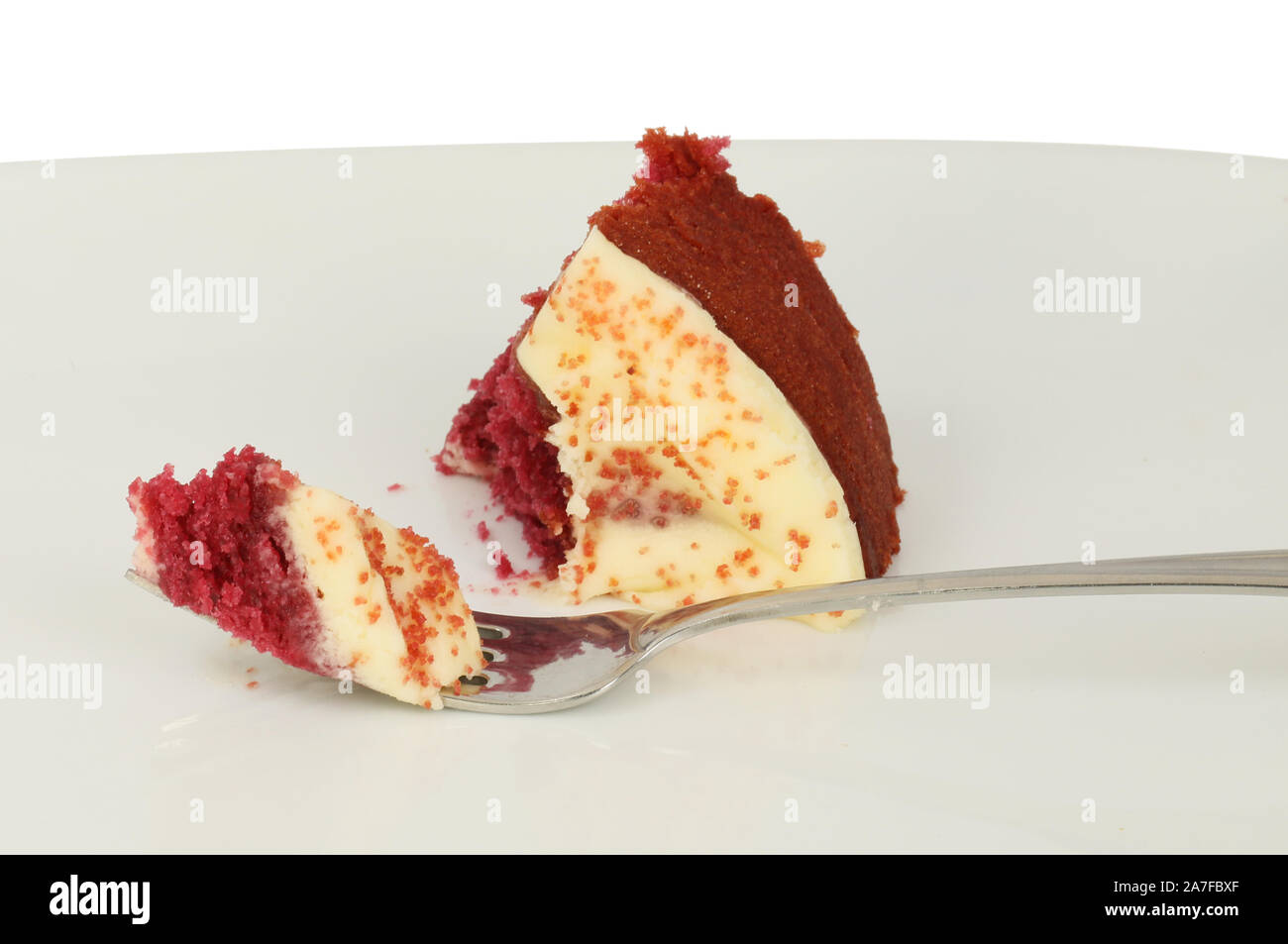 Closeup of a portion of red velvet cake with a fork on a plate against ...