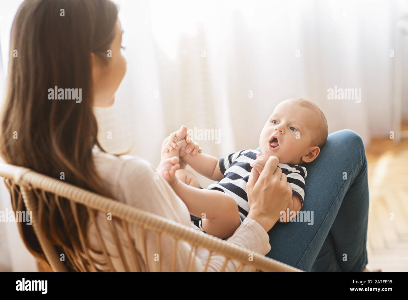 Cute little baby lying on mother's lap and cooing Stock Photo - Alamy