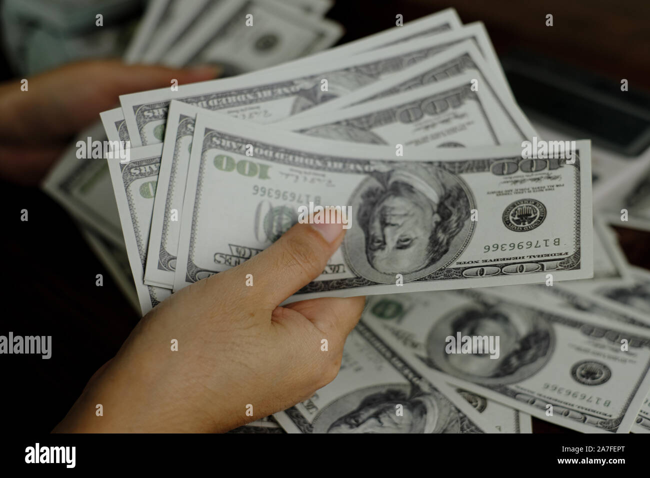 Hand holding smartphone and calculator on a stack of 100 US dollars ...