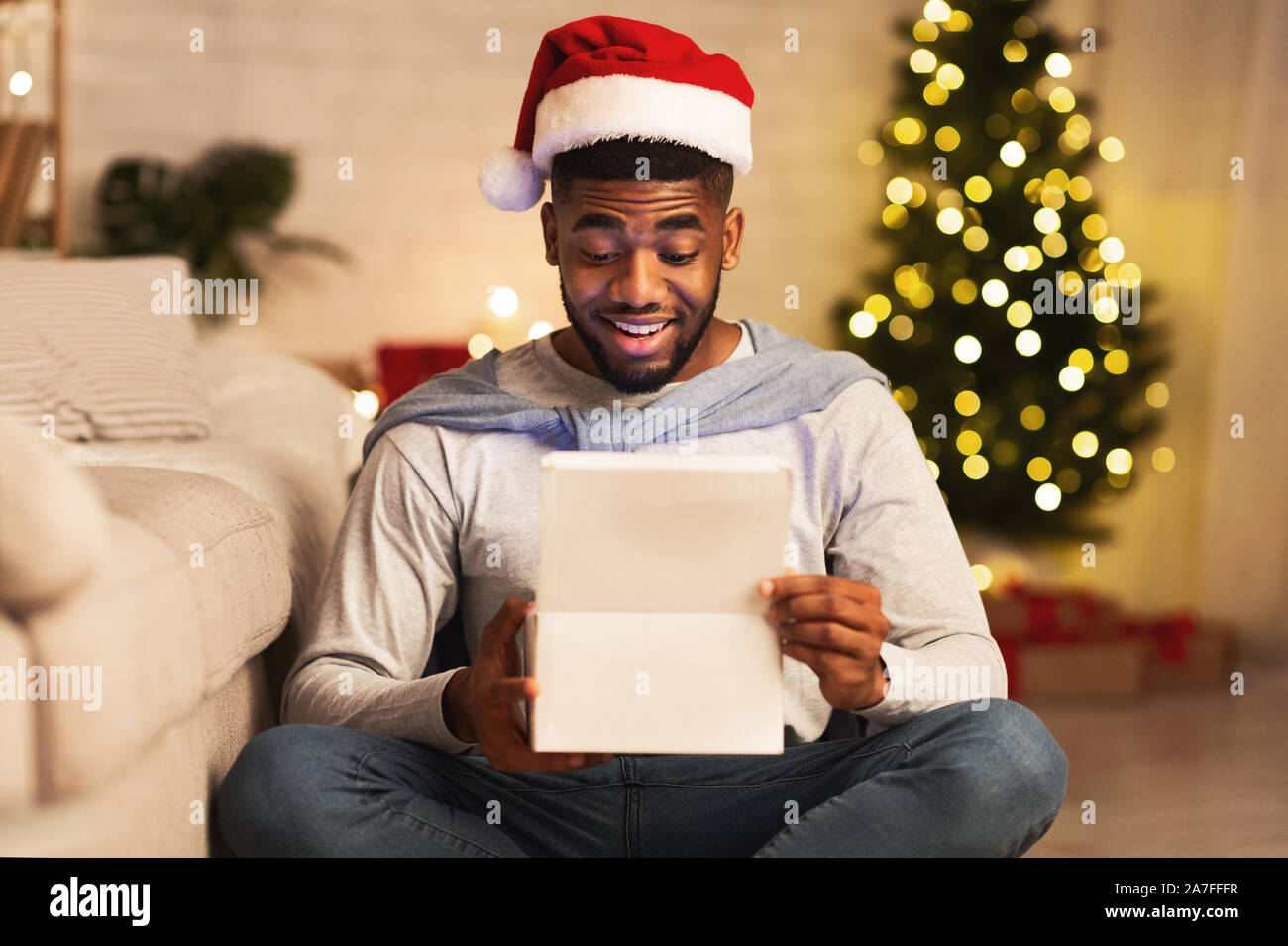 Christmas gift. Happy black guy opening box Stock Photo - Alamy