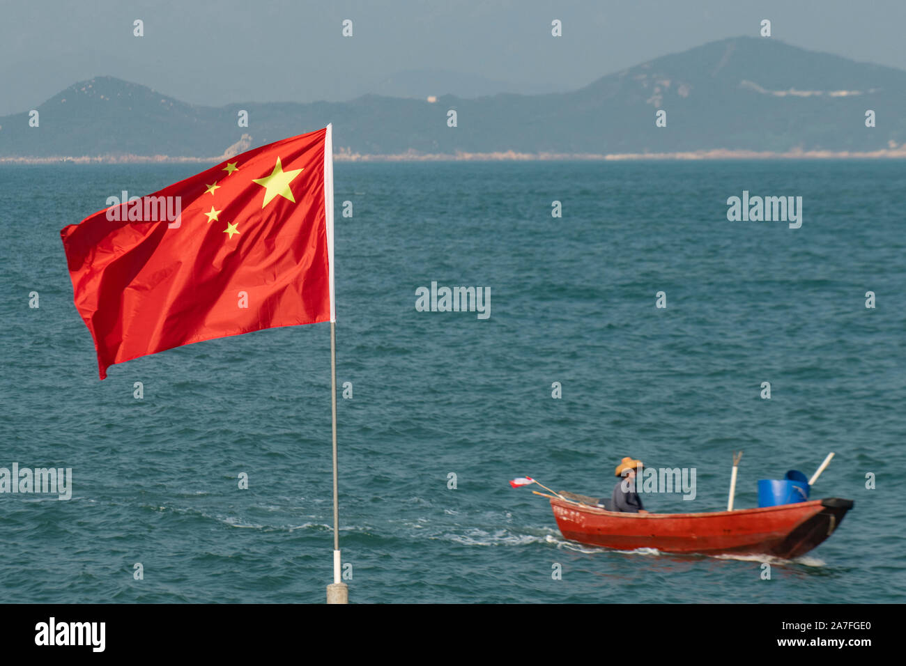 The Chinese flag flies from a rock at sea by Lamma Island, Hong Kong ...