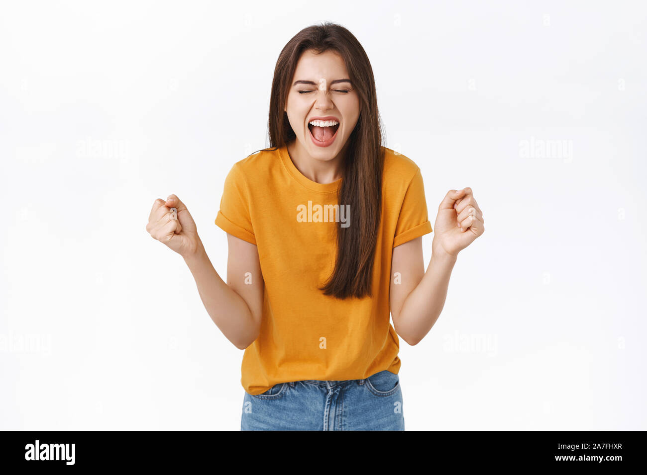 Relieved, happy woman rejoicing in yellow t-shirt, clench fists and ...