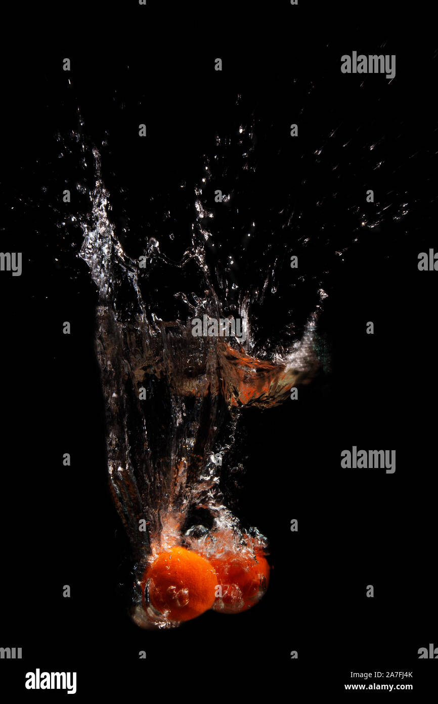 Two mandarins fall into the water on a black background Stock Photo - Alamy