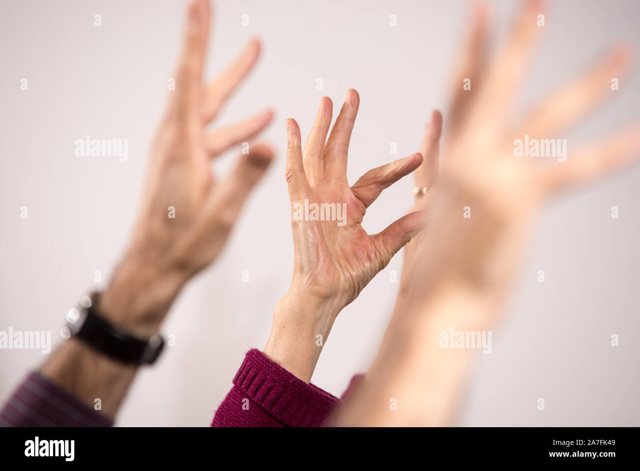 Senior citizens hands raised against a neutral background Stock Photo ...