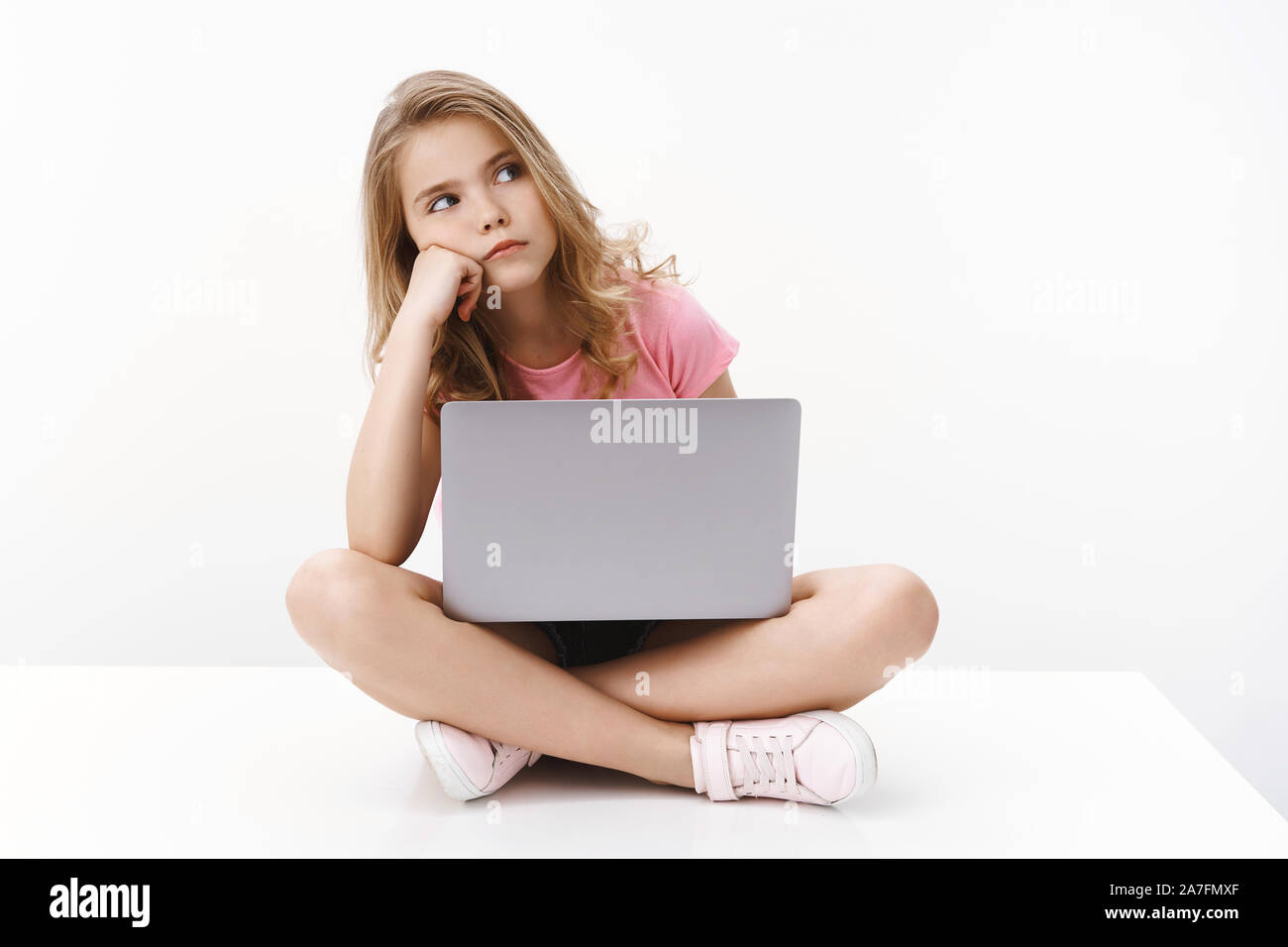 Bored uninterested cute fair-haired young child girl, sitting crossed ...