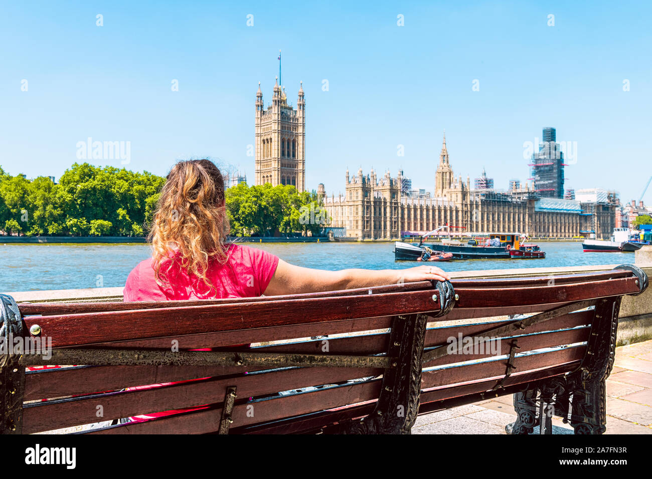 Young woman sitting on bench in London looking at cityscape skyline of ...
