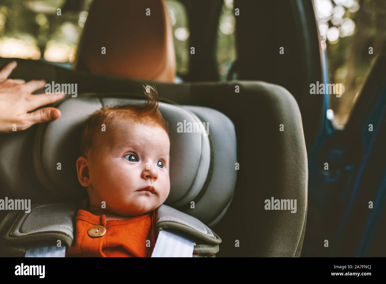 Baby sitting in safety rear-facing car seat looking at window family ...