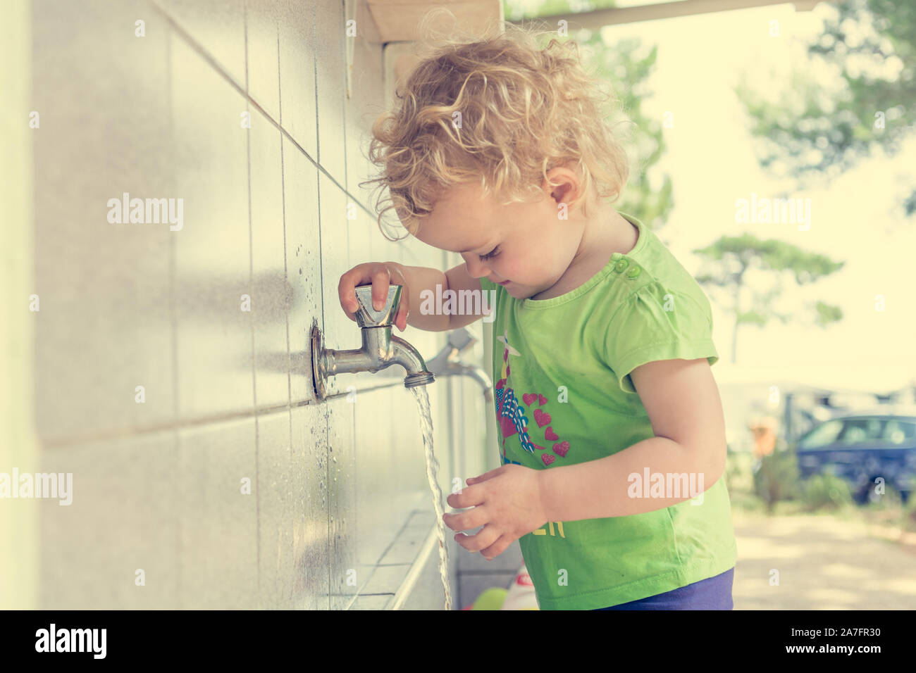 Little girl playing with water and opening a pipe Stock Photo - Alamy