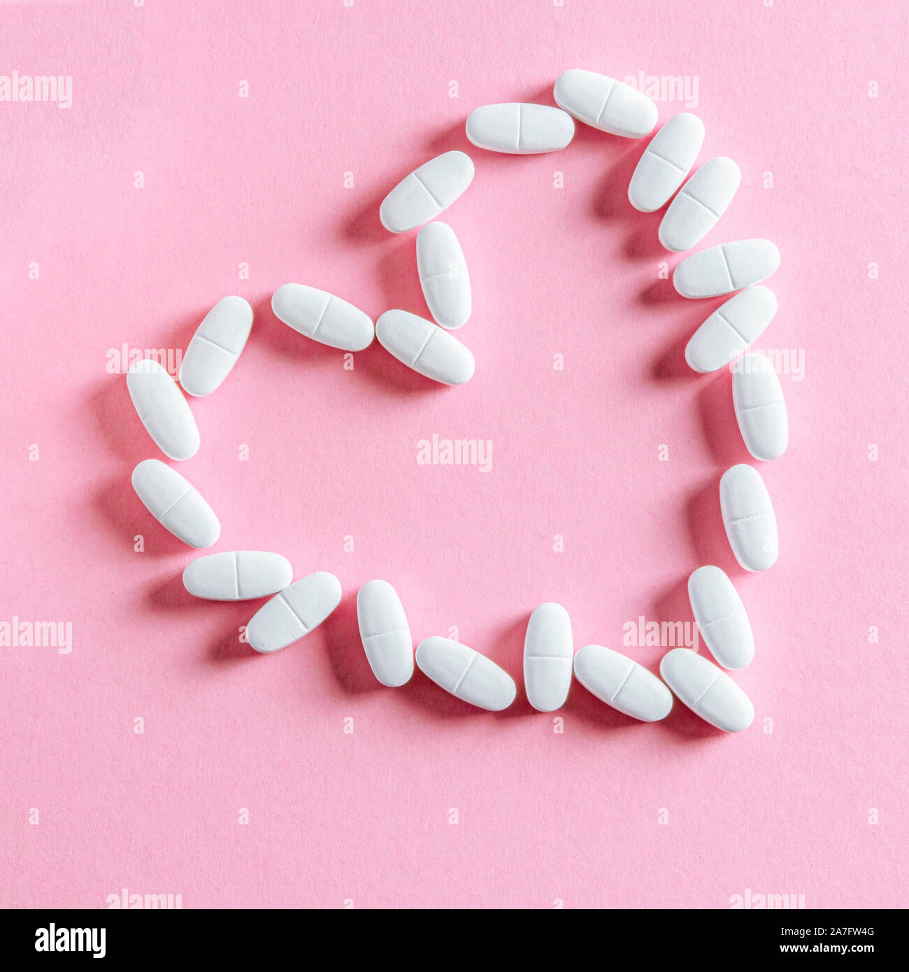 White oval heart-shaped tablets lie on a pink background Stock Photo ...