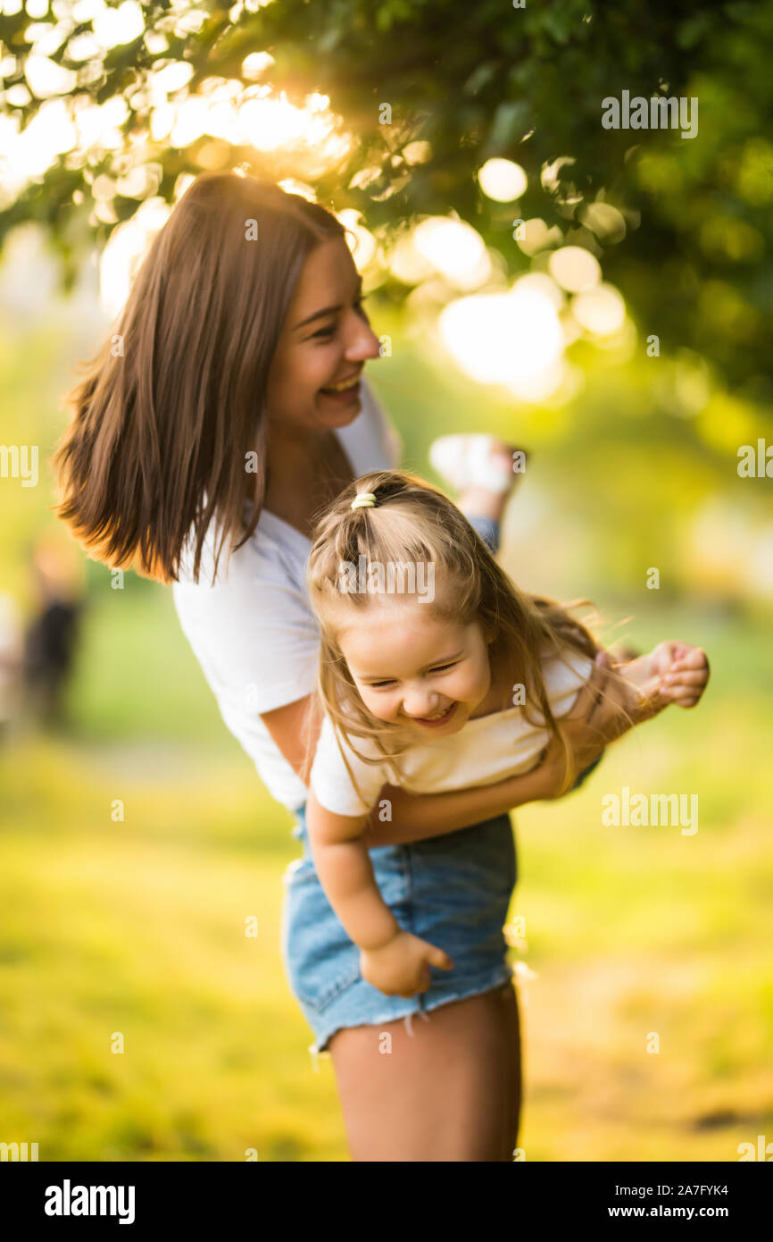 Mother and daughter playing circling around at the park on beautiful ...