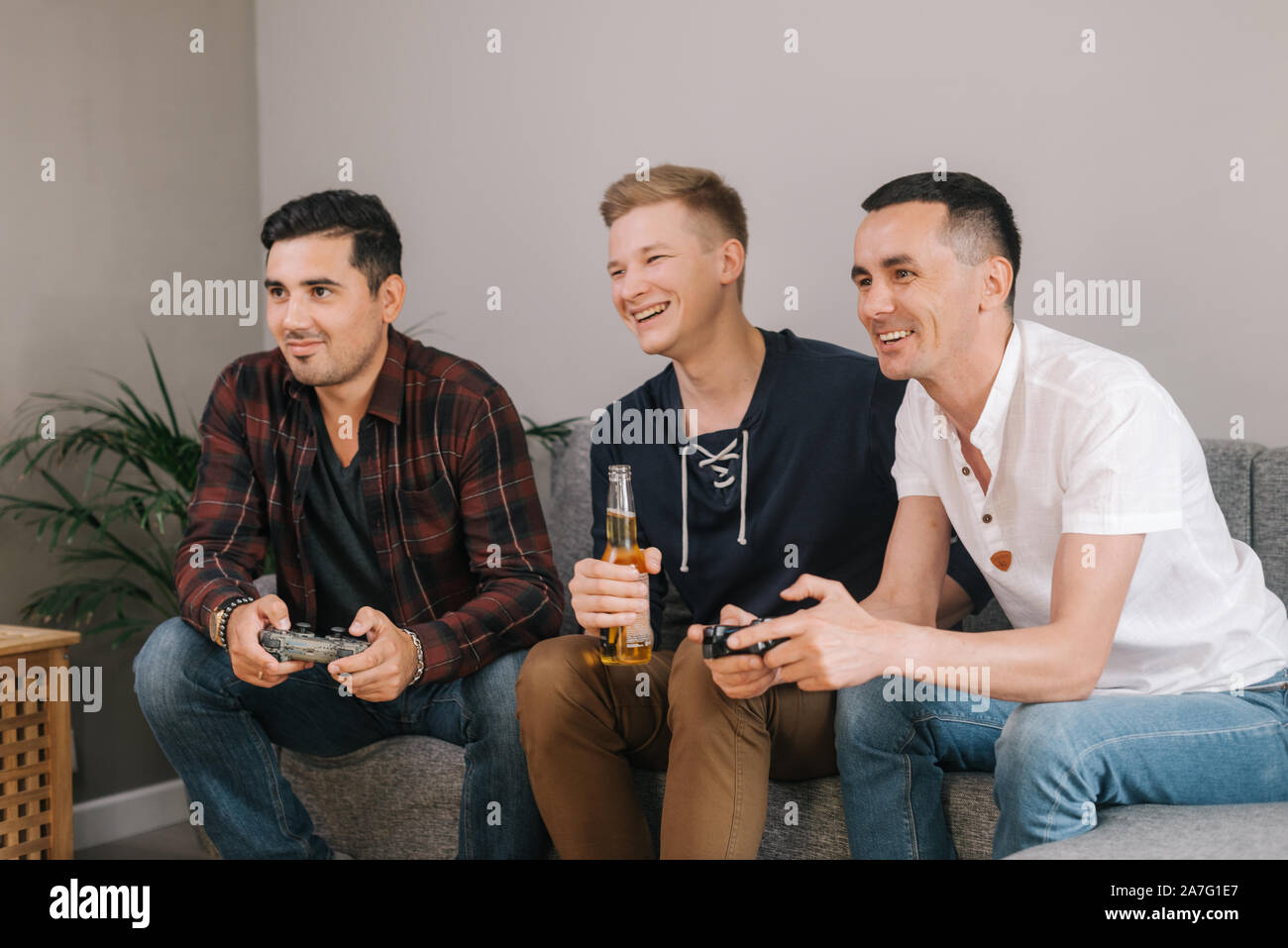 Three handsome young friends having fun on evening playing video games ...